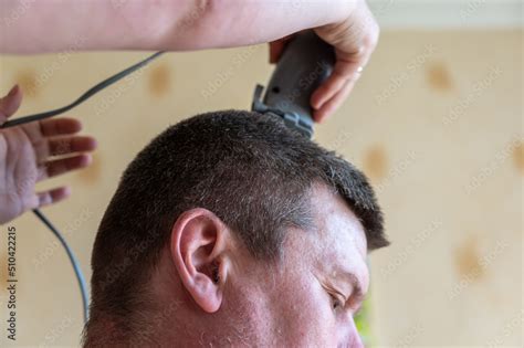 Haircut For A Grown Man A Woman S Hand With An Electric Hair Clipper Cuts Short Graying Hair
