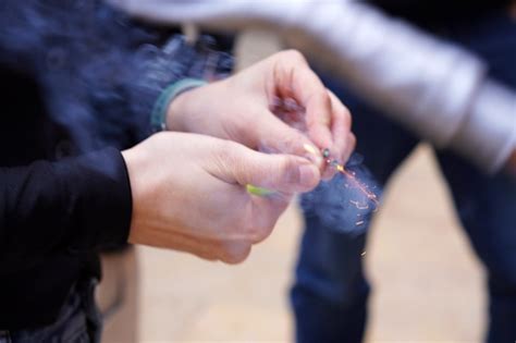 Teenager Lighting The Fuse Of A Firecracker During A Celebration While