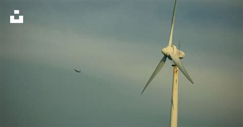 Foto Zum Thema Eine Windkraftanlage Und Ein Flugzeug Das Am Himmel