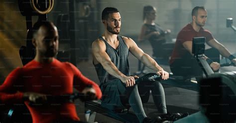 체육관에서 로잉 머신에서 스포츠 훈련을 받는 소수의 운동 선수 초점은 중간에있는 사람에게 있습니다 사진 Unsplash의 세르비아 이미지