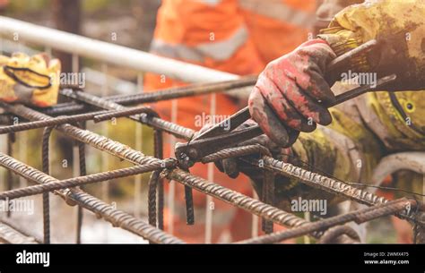 A Worker Uses Steel Tying Wire To Fasten Steel Rods To Reinforcement Bars Close Up Reinforced