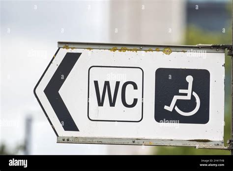 A Directional Sign Indicating The Location Of Restrooms Featuring Symbols For Standard And