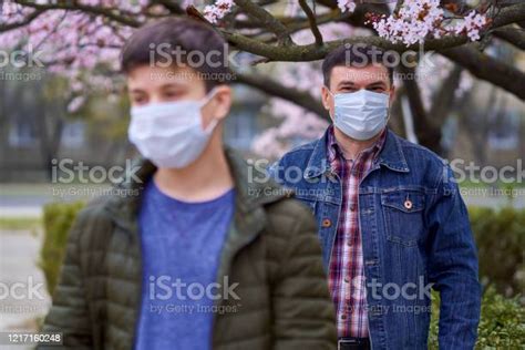 얼굴 마스크를 가진 아버지와 아들은 도시 야외 피는 나무 봄 시즌 꽃 시간 먼지가 공기로부터 알레르기와 건강 보호의 개념 보호