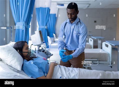 Diverse Male Doctor Filling Iv Drip On Female Patients Hand In Bed In