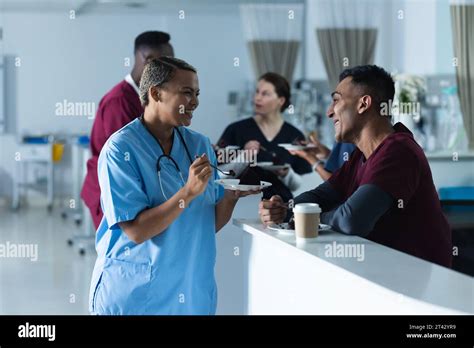 Happy Diverse Male And Female Doctors Eating Birthday Cake At Reception