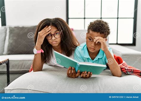Two Siblings Lying On The Sofa Reading A Book Worried And Stressed