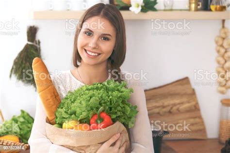 웃 고 하는 동안 야채와 과일의 전체 종이 가방을 들고 젊은 행복 한 여자 여 자가 만든 쇼핑 Kitche에서 요리에 대 한