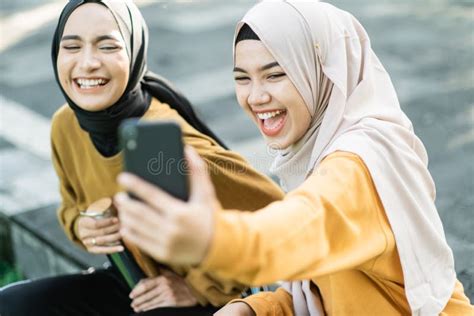 Two Girls Wearing Hijab Laughing When Looking Video Together With Smartphone In The Afternoon