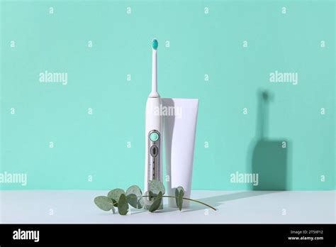 Electric Toothbrush With Toothpaste And Eucalyptus Branch On Color
