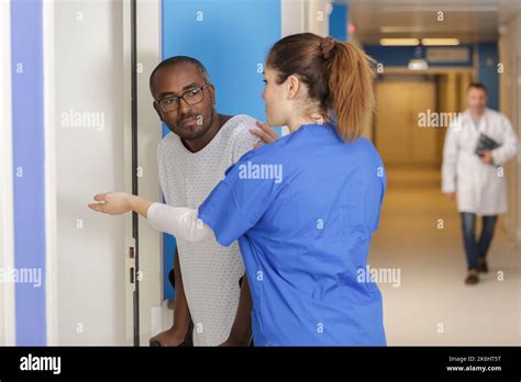 Female Nurse Helping Patient To Walk Using Walker In Hospital Stock