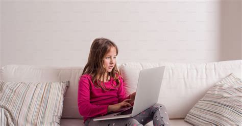 집에서 노트북 컴퓨터로 소파에 앉아 있는 어린 소녀 Pc를 사용하여 실내에서 노는 행복한 아이 사진 Unsplash의 작다 이미지