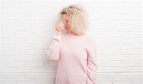 흰색 벽돌 벽에 곱슬 머리 젊은 금발의 여 자가 피곤 바르고 코와 눈 피로 두통 느낌 스트레스와 좌절 개념입니다 검안에 대한