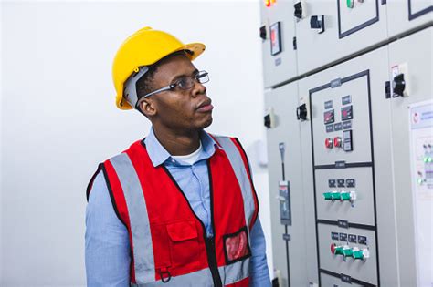 아프리카계 미국인 노동자는 전자 제어실에서 일을 하고 기계 기술자는 공장 전기 장비를 검사하고 산업 플랜트 엔지니어는 시스템을 유지 관리할 계획입니다 1개월에 대한 스톡