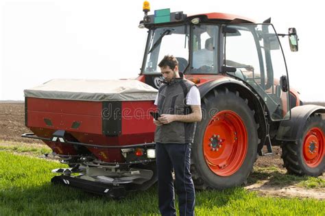 Young Farm Worker Next To Tractor Using Digital Tablet Tractor