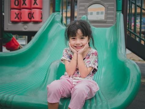 Premium Photo Portrait Of Cute Smiling Girl Sliding In Playground