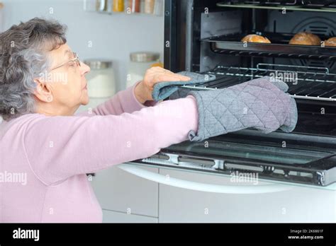 Elderly Woman Removing Tray From Oven Stock Photo Alamy