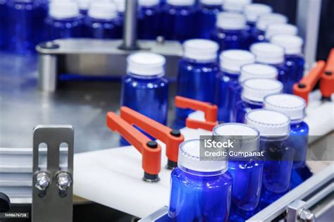 의료 공장의 충전 기계에서 컨베이어 벨트의 생산 라인에 있는 파란색 플라스틱 병 제약 제조 0명에 대한 스톡 사진 및 기타