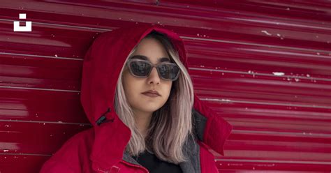 A Woman In A Red Jacket Leaning Against A Red Wall Photo Free
