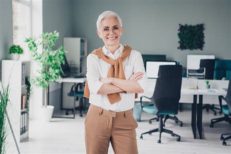 똑똑한 노인 수석 여성 교차 손 자신감있는 착용 공식 편안한 현대 사무실 로프트 룸 인테리어 실내 작업 공간 사진 55 59세에