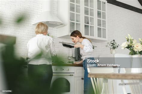 나이가 많은 어머니는 부엌에서 음식을 준비하고 딸은 차를 마시고 어머니를 바라봅니다 부엌에 대한 스톡 사진 및 기타 이미지 부엌 여자 요리하기 음식 준비 Istock
