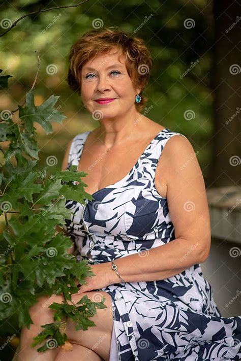 A Woman In A Floral Dress Poses Gracefully Among Greener Stock Image
