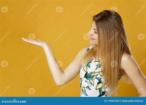 Young Pretty Blond Woman Presenting Your Product Over Yellow Background