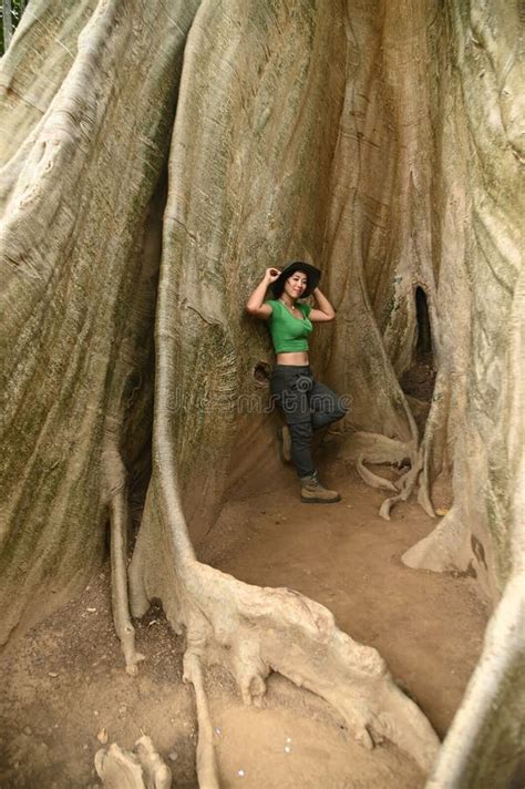 Pretty Asian Woman Posing In A Standing And Happy Pose At The Base Of A Big Tree And This Tree