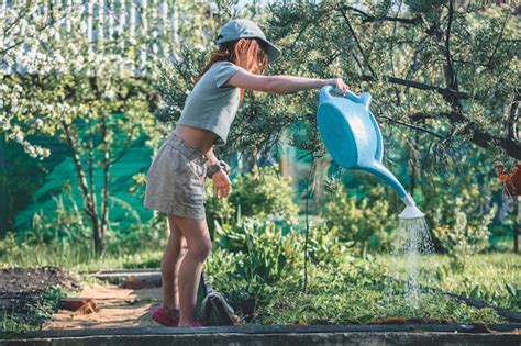 Premium Photo Girl Watering Blooming Tree With Watering Pot In The Garden