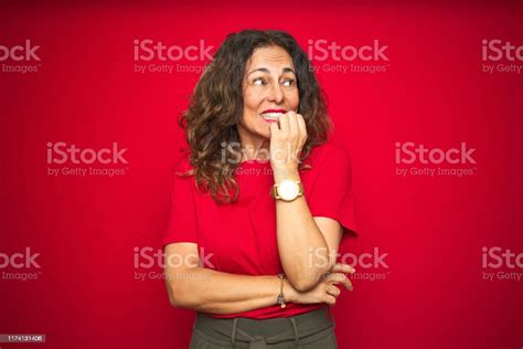 빨간 고립 된 배경 위에 곱슬 머리를 가진 중년 노인 여성은 손톱을 물고 입에 손을 긴장 찾고 불안 문제 T 셔츠에 대한 스톡 사진 및 기타 이미지 Istock