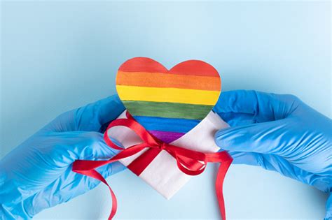 보호 블루 장갑을 끼고 수제 무지개 종이 하트와 빨간 리본이 달린 선물 상자를 들고 있는 손 개념에 대한 스톡 사진 및 기타