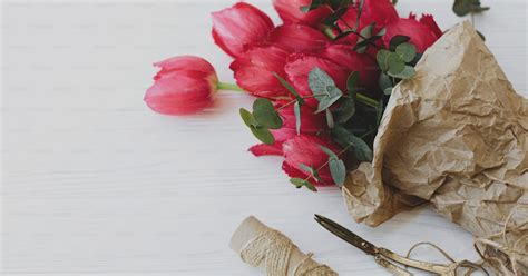 아름다운 빨간 튤립과 유칼립투스 꽃다발은 소박한 흰색 나무 배경에 가위와 꼬기가 있는 공예 종이에 있습니다 인사말 카드 서식 파일입니다 행복한 여성의 날 해피 어머니의