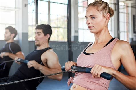 Focused On Fitness A Group Of People Working Out On Rowing Machines In