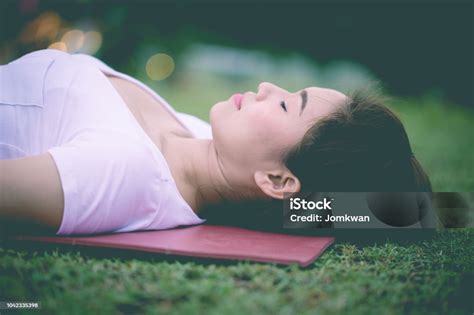 닫는 아름 다운 매력적인 아시아 여자 연습 요가 시체 자세 또는 Savasana 포즈 요가 대 한 녹색 잔디와 요가 매트에 누워