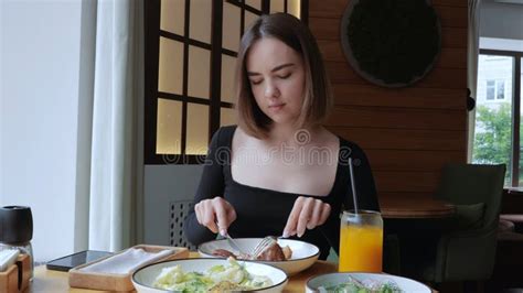 A Cute Brunette In A Restaurant Happily Eats A Meat Dish With Fried