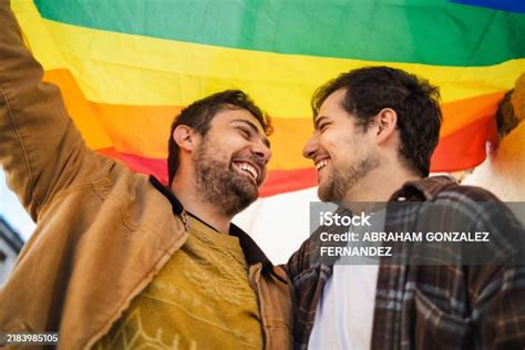 무지개 깃발을 들고 서로에게 미소 지으며 Lgbtq 플러스 프라이드를 축하하는 행복한 게이 커플 20 24세에 대한 스톡 사진 및 기타 이미지 Istock