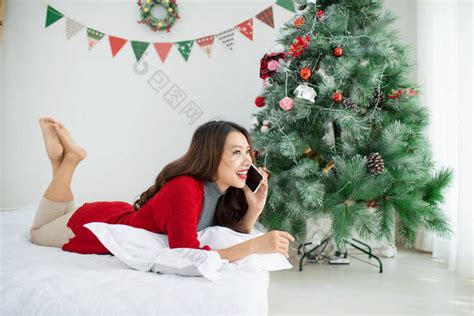年轻微笑亚洲女人正在使用移动电话圣诞节和图片 包图网企业站