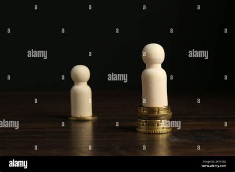 Financial Inequality One Wooden Figure With Bigger Stack Of Coins Than