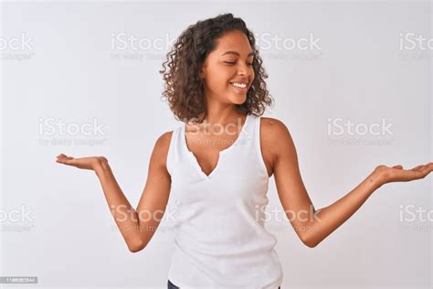두 손을 열고 손바닥을 보여주는 고립 된 흰색 배경 위에 서있는 캐주얼 한 티셔츠를 입은 젊은 브라질 여성 제시 및 광고 비교
