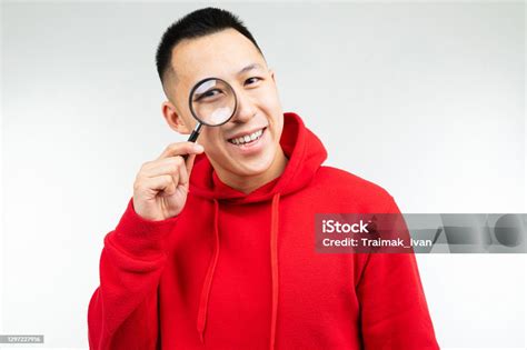 빨간 스웨터에 갈색 머리 남자 흰색 고립 된 배경에 돋보기를 통해 카메라를보고 돋보기 광학 기기에 대한 스톡 사진 및 기타
