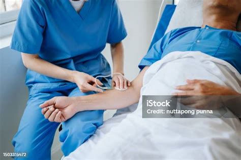 친절한 여성 간호사가 침대에서 쉬고 있는 환자를 검진합니다 그녀는 병원에서 성공적인 수술 후 완전히 회복하는 동안 태블릿을