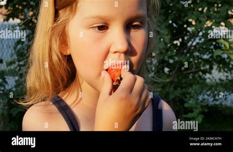 Portrait Beautiful Blonde Teenage Girl Bites Off A Strawberry In Her