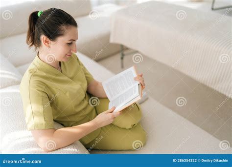 Top View Of Pensive Female Masseuse Therapist In Uniform Sitting Posing