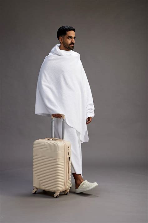 A Man Wearing Ehram Pulling A Carry On