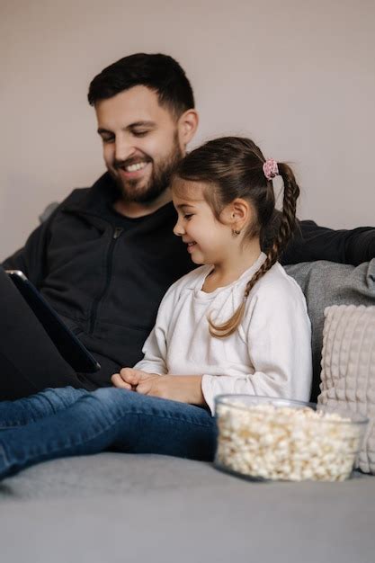 Ador Vel Menina Assistindo Desenhos Animados Na Mesa Com O Pai Filha Com O Pai Comendo Pipoca E