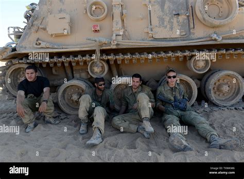 Isreali Soldiers Rest Beside An Armored Personnel Carrier In A Staging