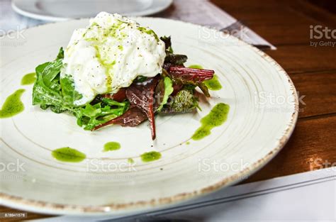 세라믹 접시에 전통적인 이탈리아 전문 Burrata 치즈 흰색 소박한 나무 테이블 위에 올리브 오일 그린 샐러드와 함께 제공