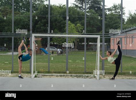 Two Girls Are Stretching Their Leg Up Together While Holding On The