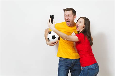 젊은 커플 남자 여자 하 고 휴대 전화에 Selfie를 종사 하는 재미 있는 미친 축구공 흰색 배경에 고립 된 지원 팀 응원