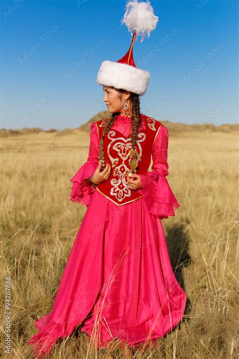 Красивая казахская девушка в национальном костюме танцует в степи с