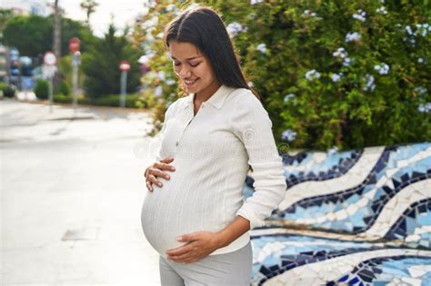 Young Latin Woman Pregnant Smiling Confident Touching Belly At Street Stock Image Image Of